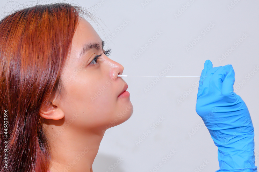Woman wearing blue medical gloves and emakes with a cotton swab a nasal ...