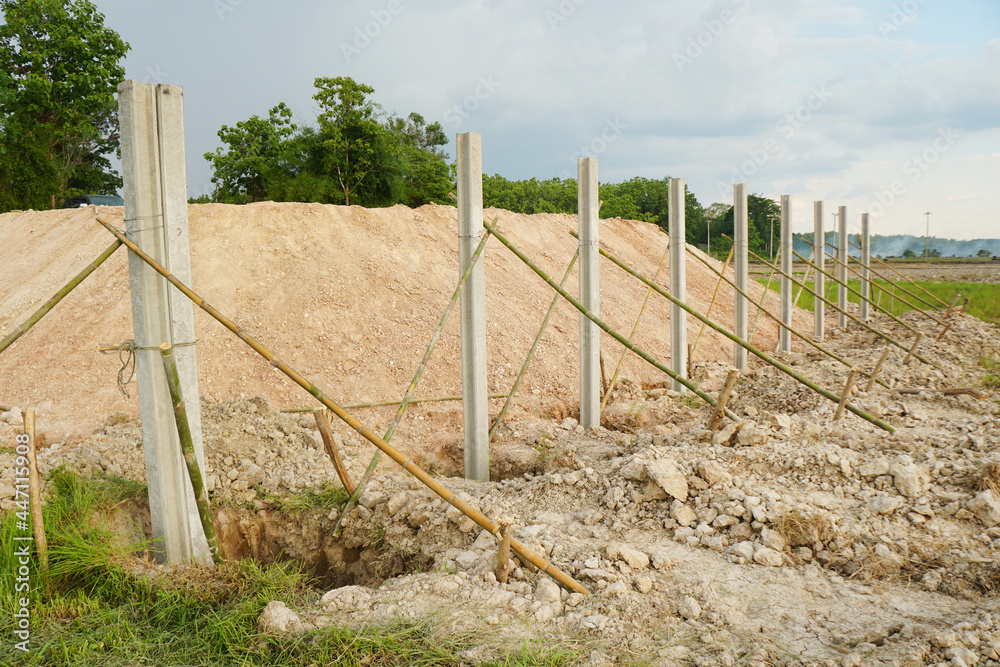 Precast concrete I-beams are placed in rows to form a fence wall ...