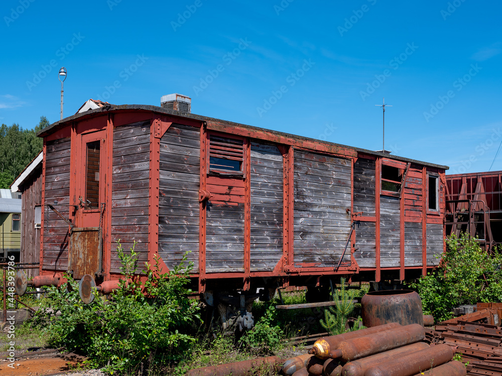 Old derelict train cart stored in a station yard. Train tracks are ...