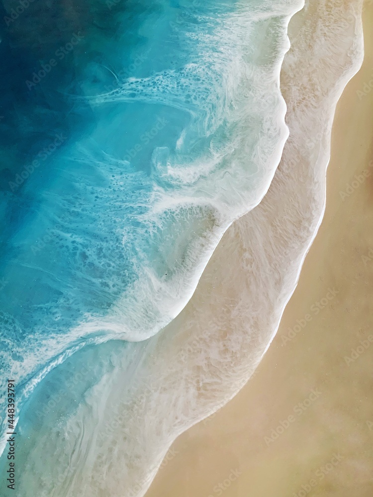 Top view on sea wave with white foam and light beige sand. Fluid, pour ...