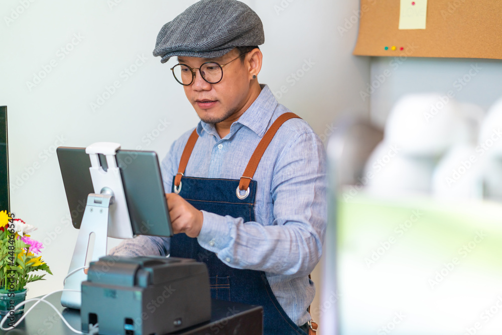 Asian man coffee shop manager walking behind bar counter working on ...