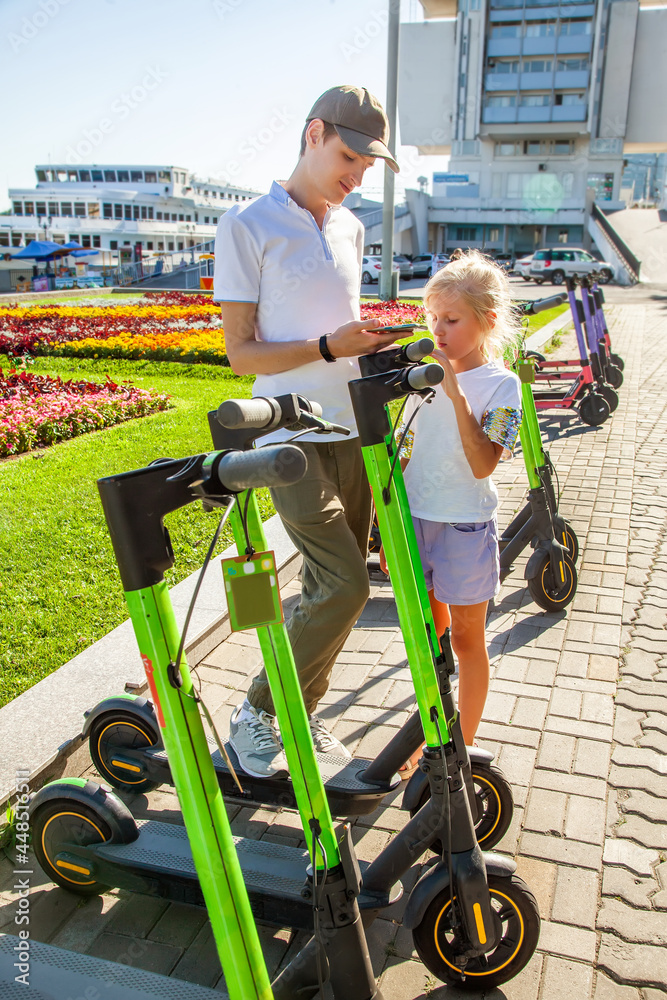 young man and girl - brother and sister - rents an electric scooter by ...