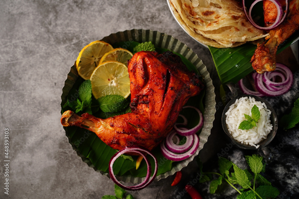 Homemade Tandoori chicken leg pieces served in a plate with roti ...