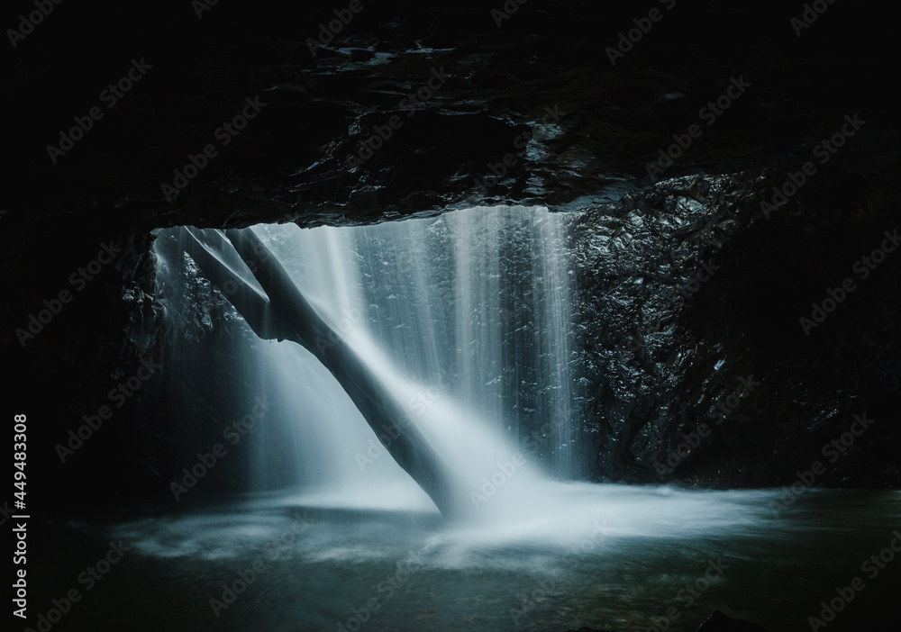 Waterfall flowing through opening in roof of cave at Natural Bridge ...