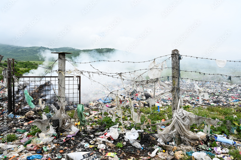 Open landfill site with burning waste. Burning pile of illegal garbage ...