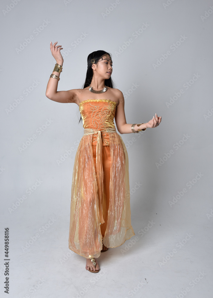 Full length portrait of pretty young asian woman wearing golden Arabian ...