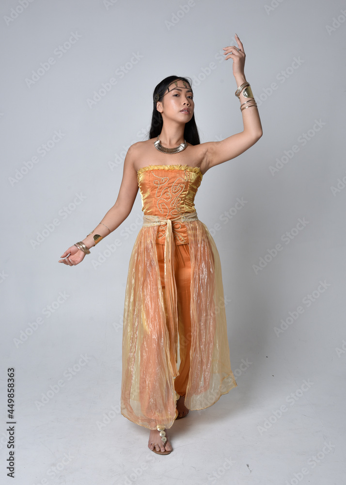 Full length portrait of pretty young asian woman wearing golden Arabian ...