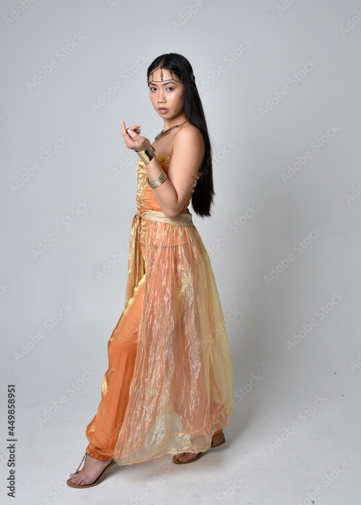 Full length portrait of pretty young asian woman wearing golden Arabian ...