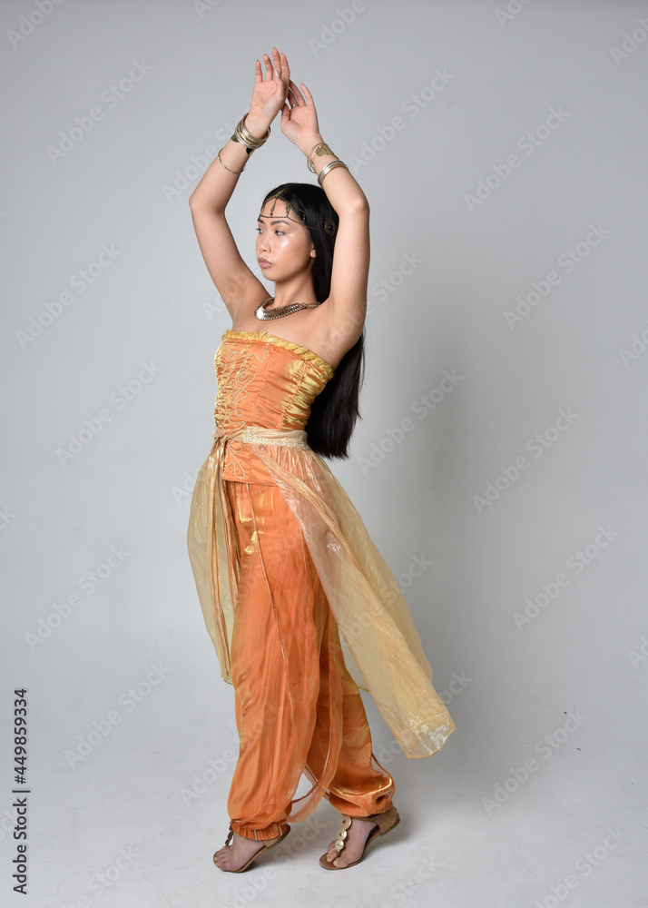Full length portrait of pretty young asian woman wearing golden Arabian ...