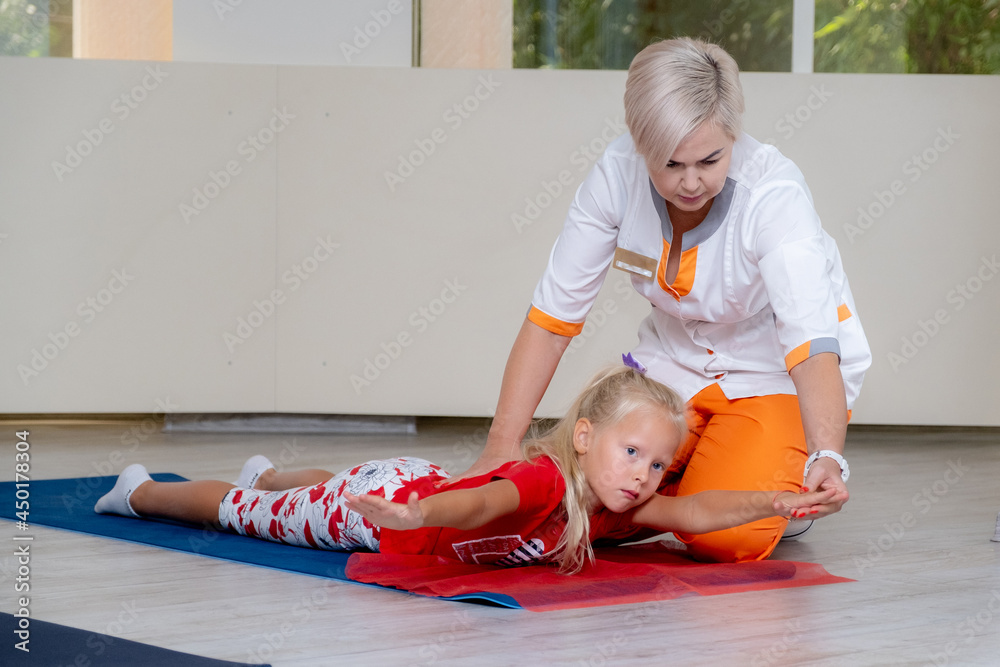 Little girl lying on fitness mat outstretching her arms to sides ...