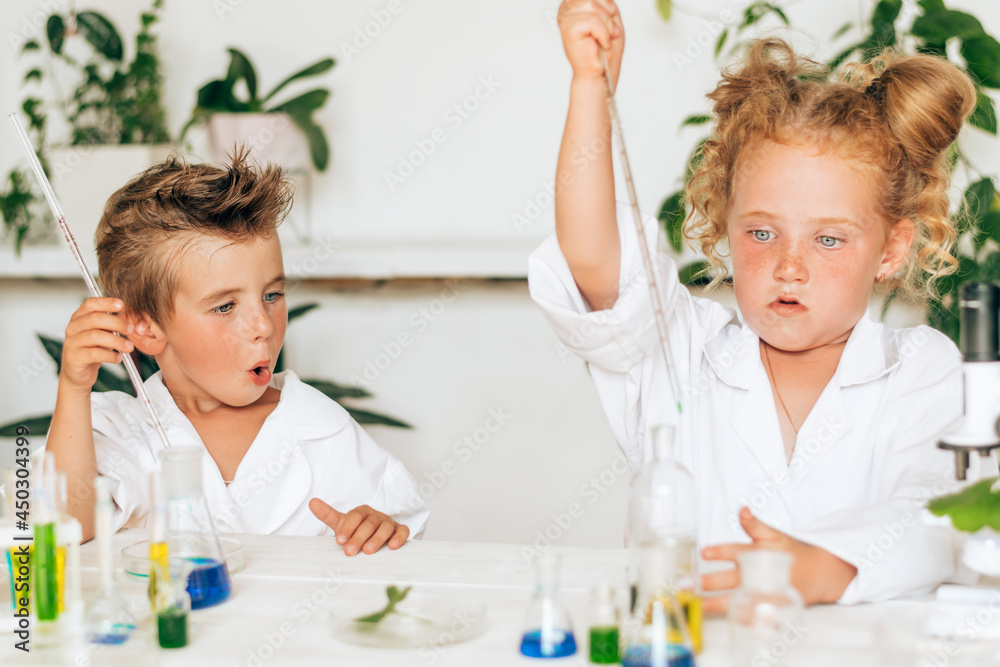 Curious little boy and girl in white uniforms conducting chemical ...