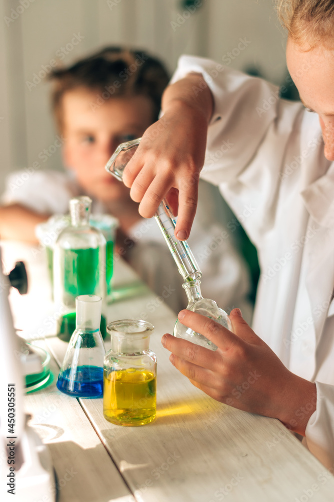 Serious little boy and girl in white uniforms conducting chemical ...