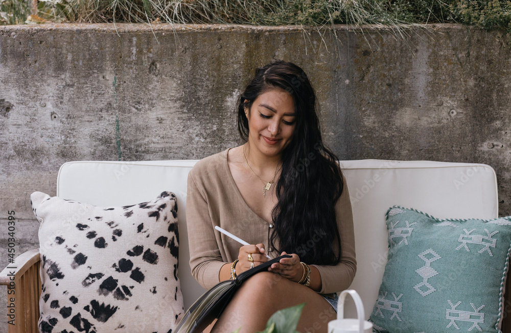 Young adult Filipino woman writing and journaling outdoors at home on ...
