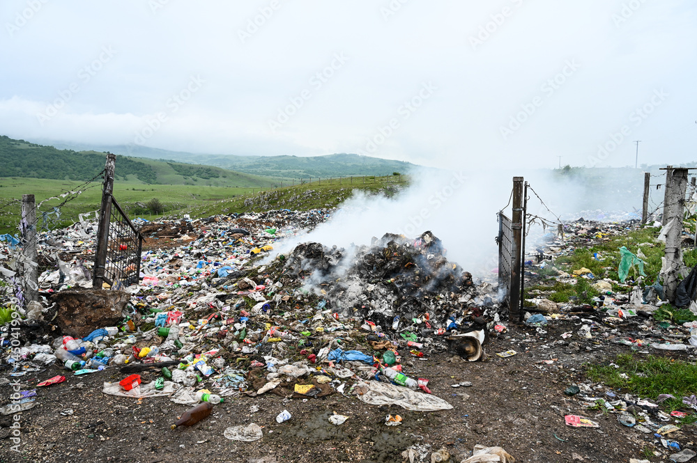 Open landfill site with burning waste. Burning pile of illegal garbage ...