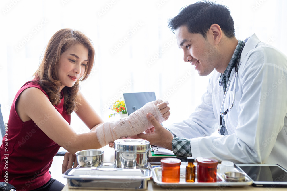 Asian Young man doctor of checking splint the arm of female patient ...