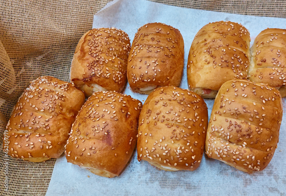 Foto de Stock Pan blanco horneado con ajonjoli llamado rollitos de jamón y queso. | Adobe Stock