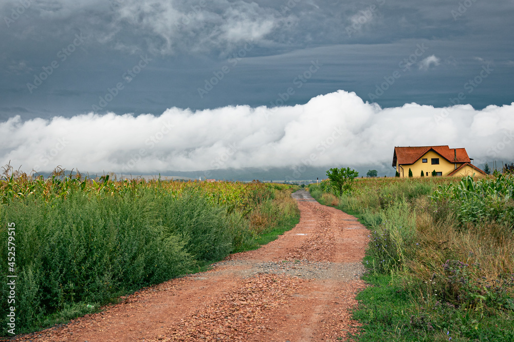 Country road leading to very low clouds at the back of a cold front in ...