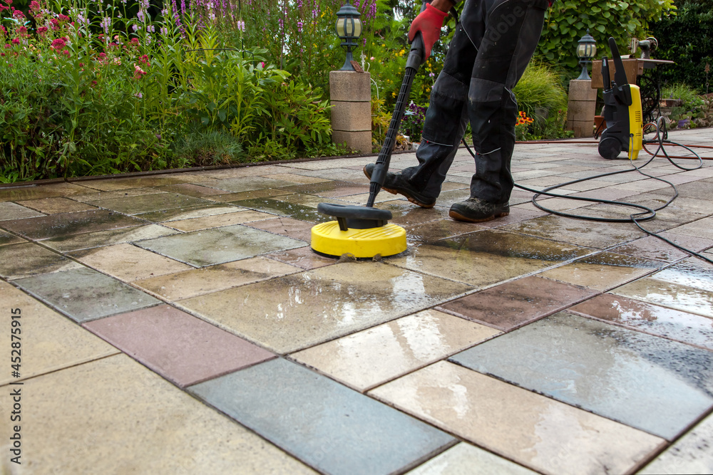 Cleaning stone slabs on patio with the high-pressure cleaner. Person ...