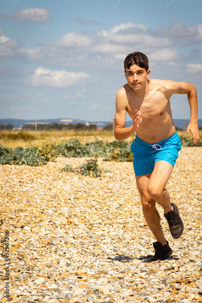 Shirtless teenage boy running on a beach Stock Photo | Adobe Stock