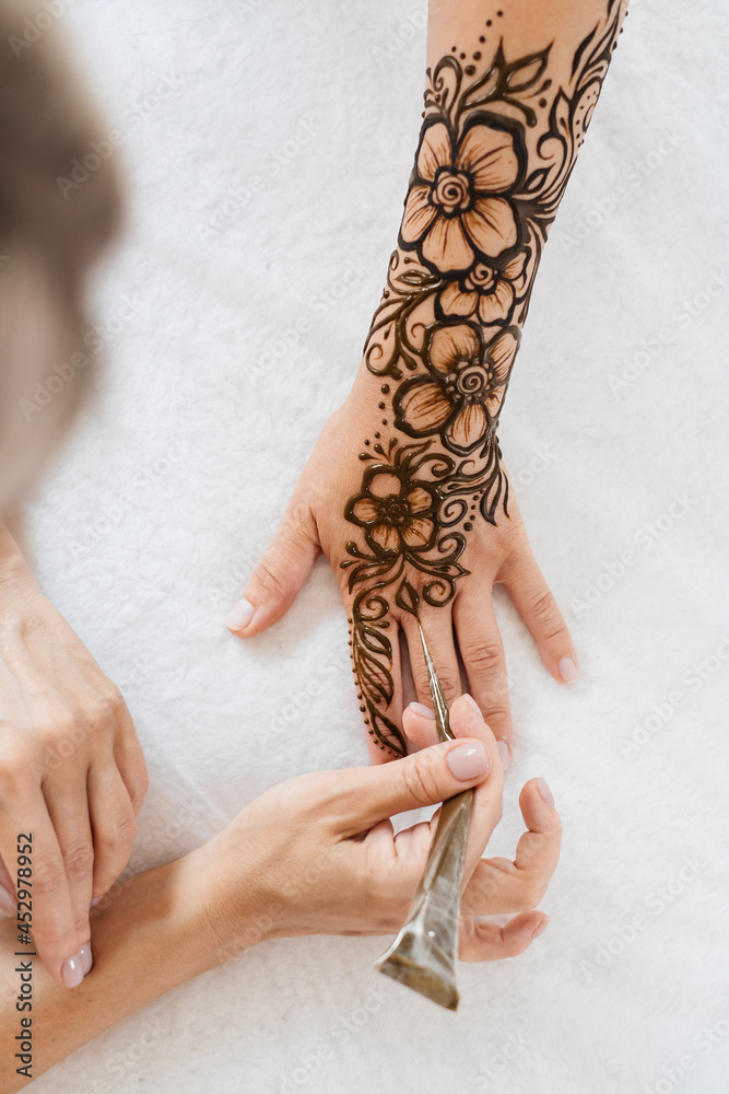Artist applying henna tattoo on women hands. Mehndi is traditional Indian decorative art, Hand ...