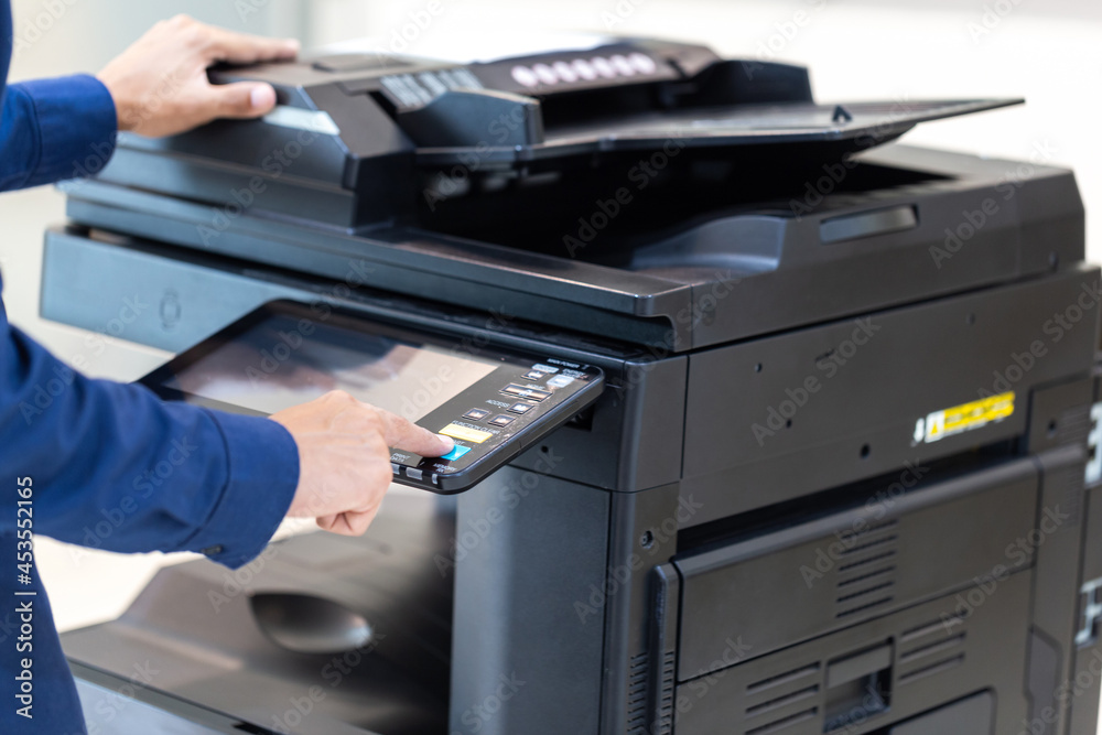 Foto Businessman press button on panel of printer photocopier network ...