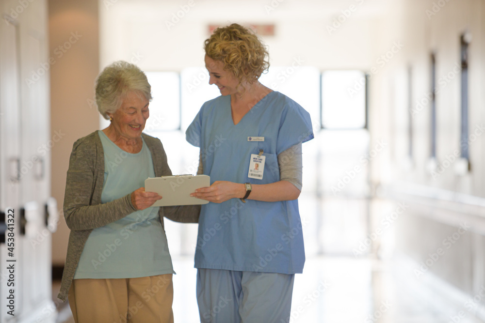 Nurse and aging patient reading chart in hospital corridor Stock Photo ...