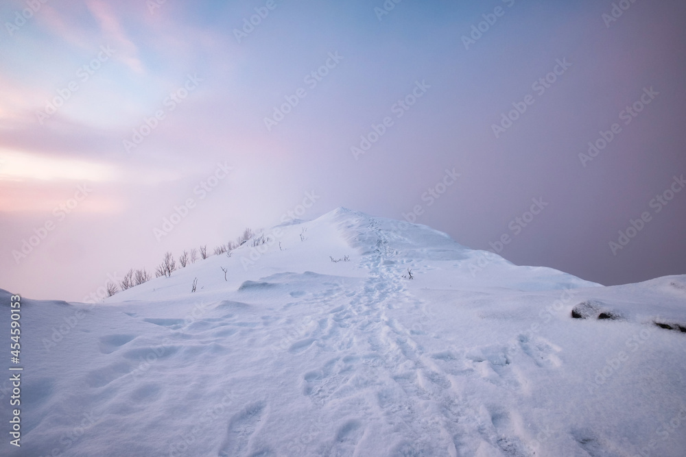 Stock-Foto „Snow covered mountain peak with footprint and colorful sky ...