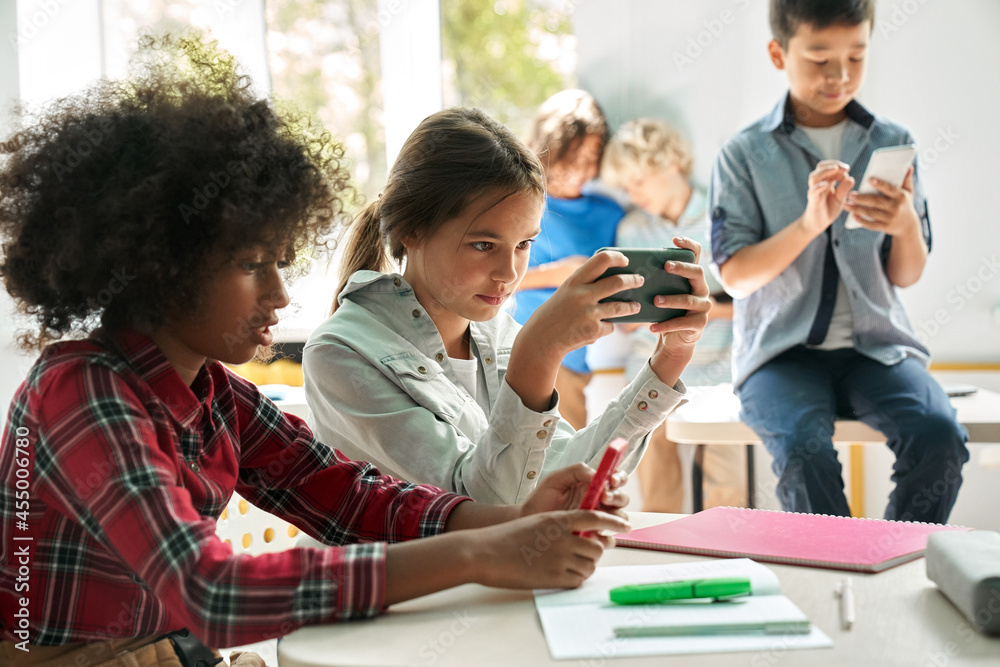 Diverse multiethnic kids students using smartphones in classroom ...