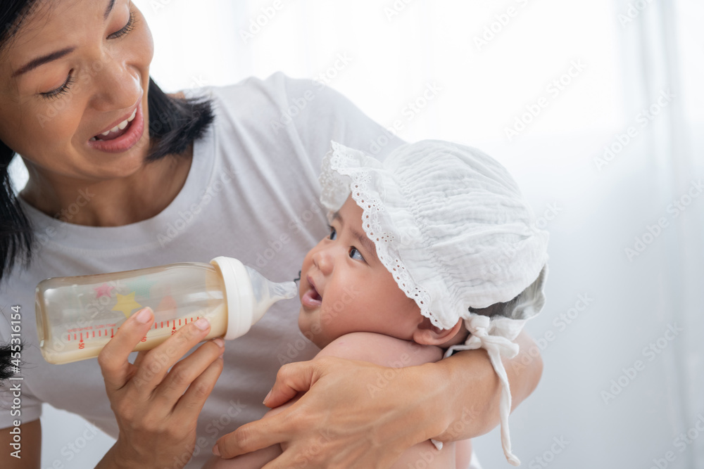 Mother holding and feeding baby from milk bottle at home. Portrait of ...