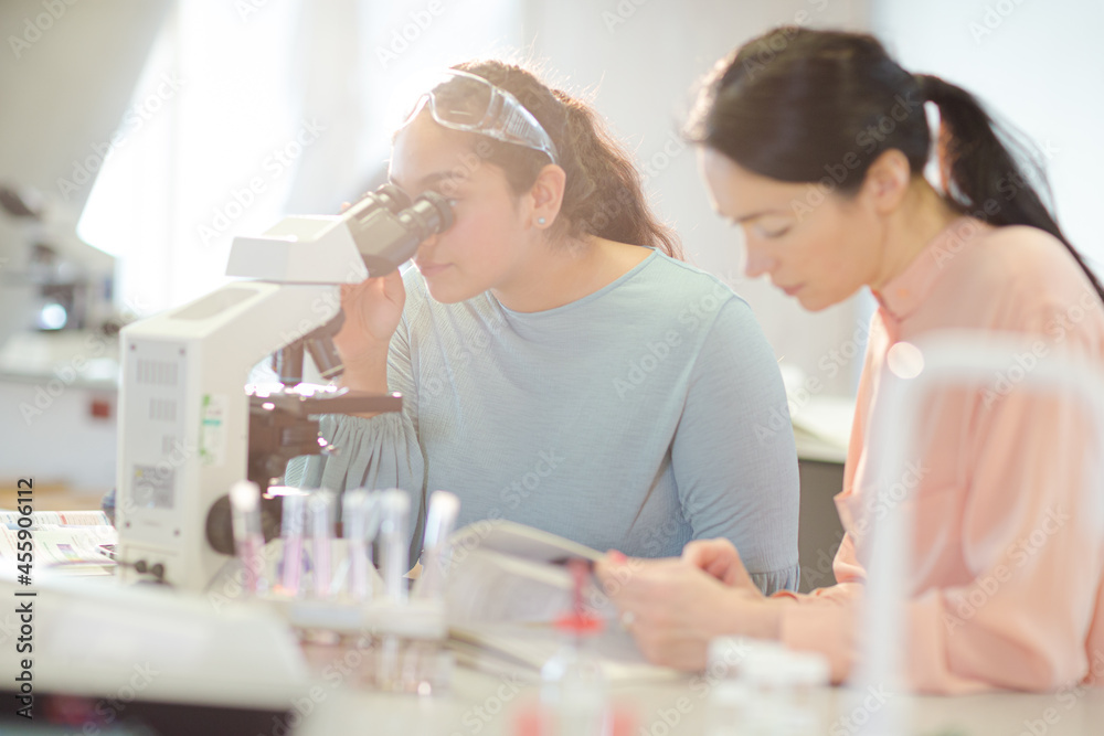 Female teacher and girl student conducting scientific experiment at ...