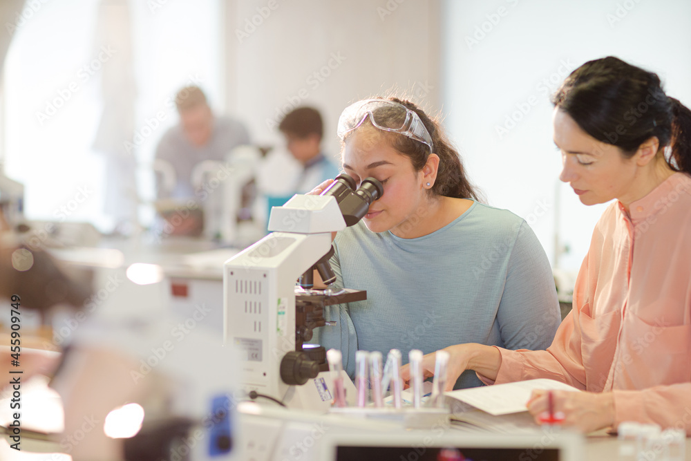 Female teacher and girl student conducting scientific experiment at ...