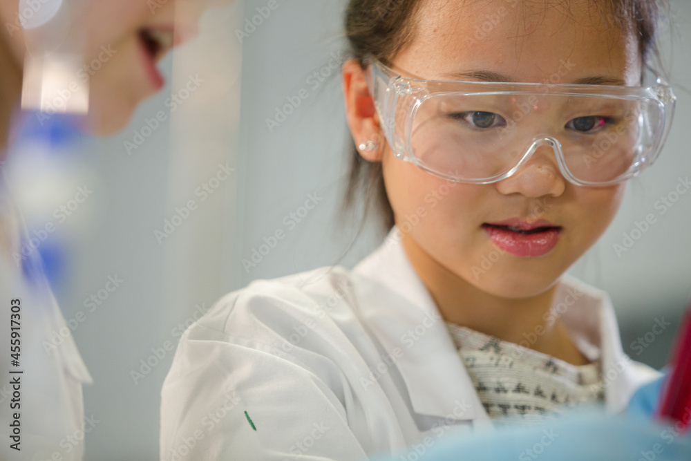 Girl student examining pink liquid, conducting scientific experiment in ...