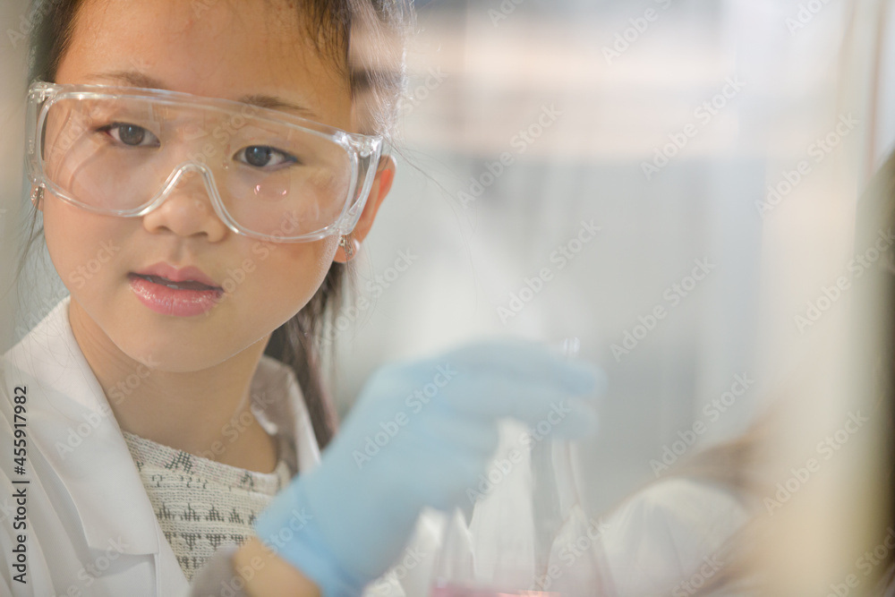 Girl student examining pink liquid, conducting scientific experiment in ...