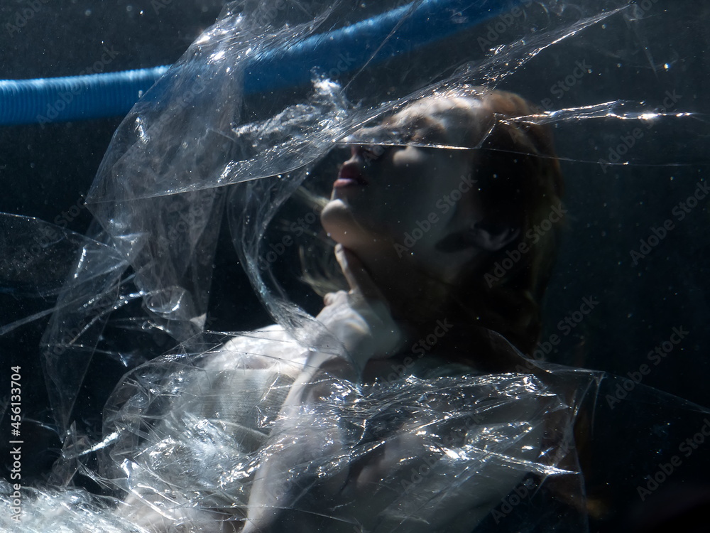 Woman swimming underwater among plastic trash. Girl drowning in sea ...