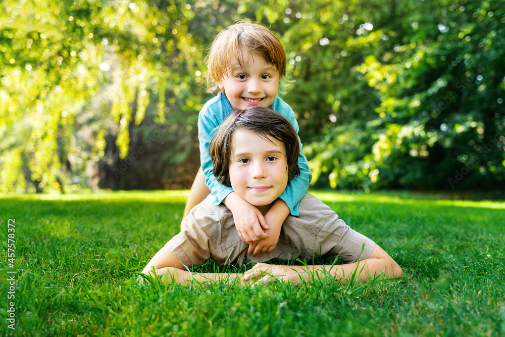 Portrait of two brothers lying on a grass and playing together in a ...