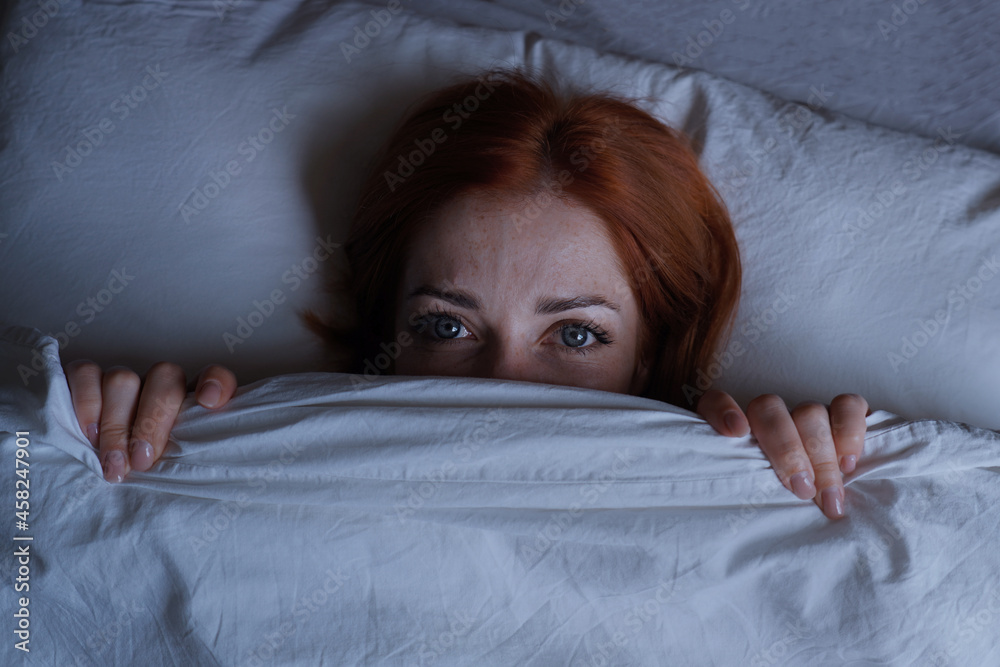 sleepless woman lying in bed hiding under duvet at night Stock Photo ...