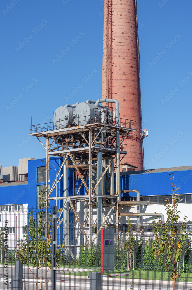 Urban landscape. Fragments of a high brick pipe and metal structure at ...