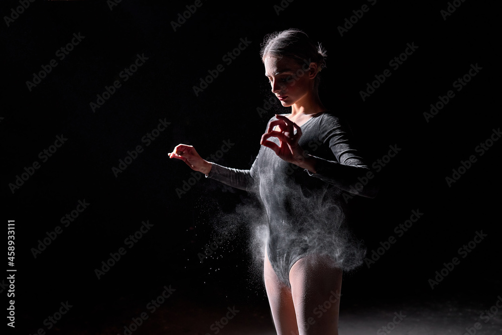 Side view on ballet dancer gymnast in studio on black background ...