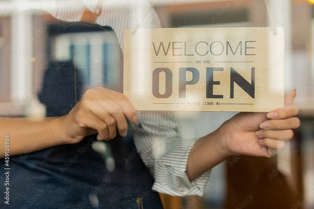 The owner of a coffee shop or restaurant hangs an open sign on the ...