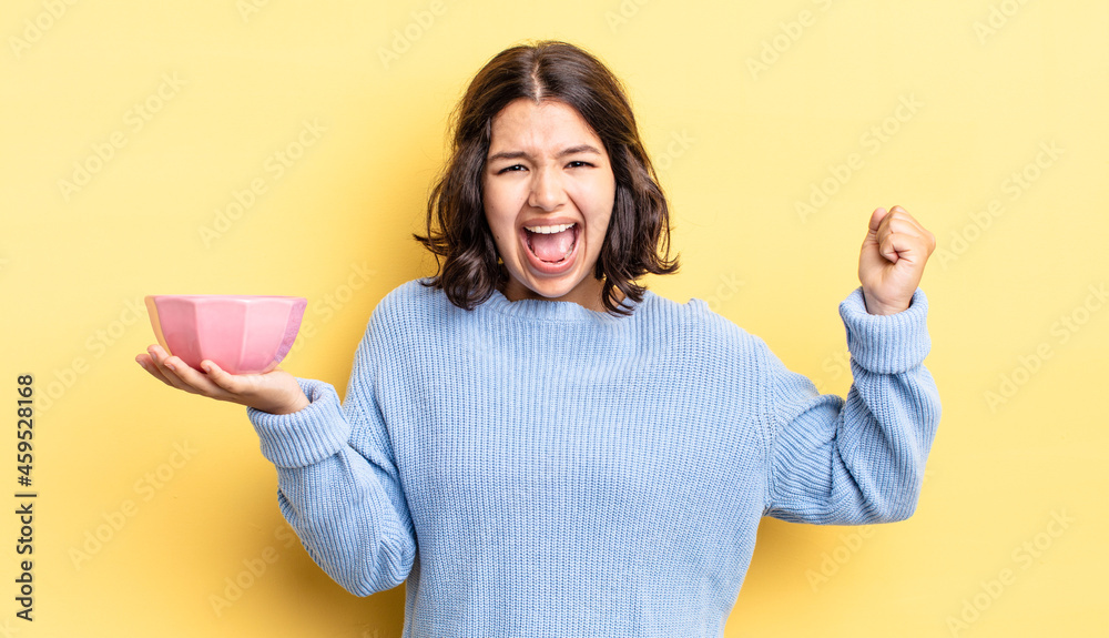 young hispanic woman shouting aggressively with an angry expression ...