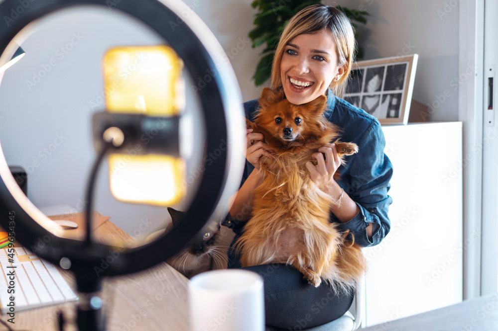 Smiling female influencer with Pomeranian dog vlogging at home Stock ...