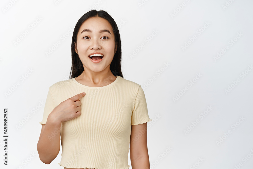 Excited happy asian girl pointing finger at herself, winning prize ...