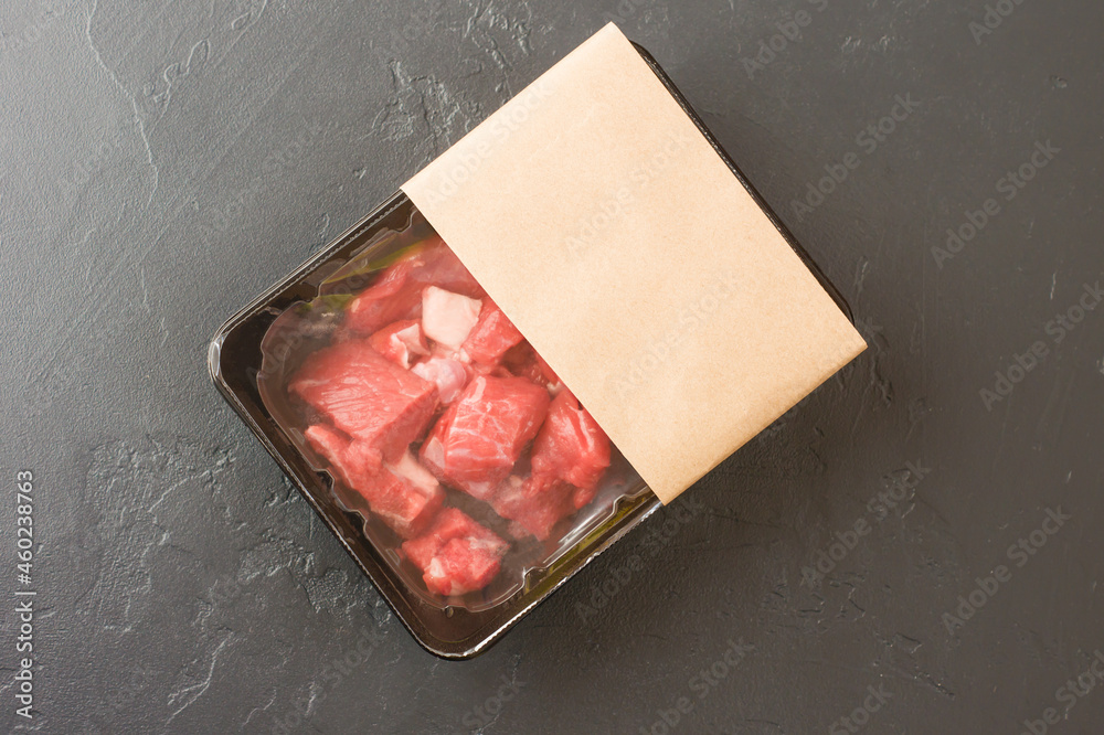 portioned pieces of fresh meat in vacuum packaging on a black ...