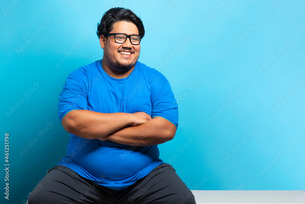 Portrait of a fat man wearing eyeglasses smiling while sitting cross ...