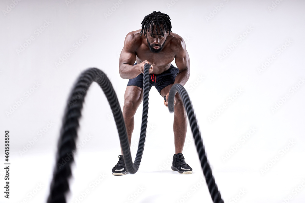 Afro muscular man working out with heavy ropes. isolated on white ...