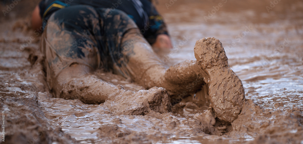 Foto de Stock Mud race runners. Crawling, passing under a barbed wire ...