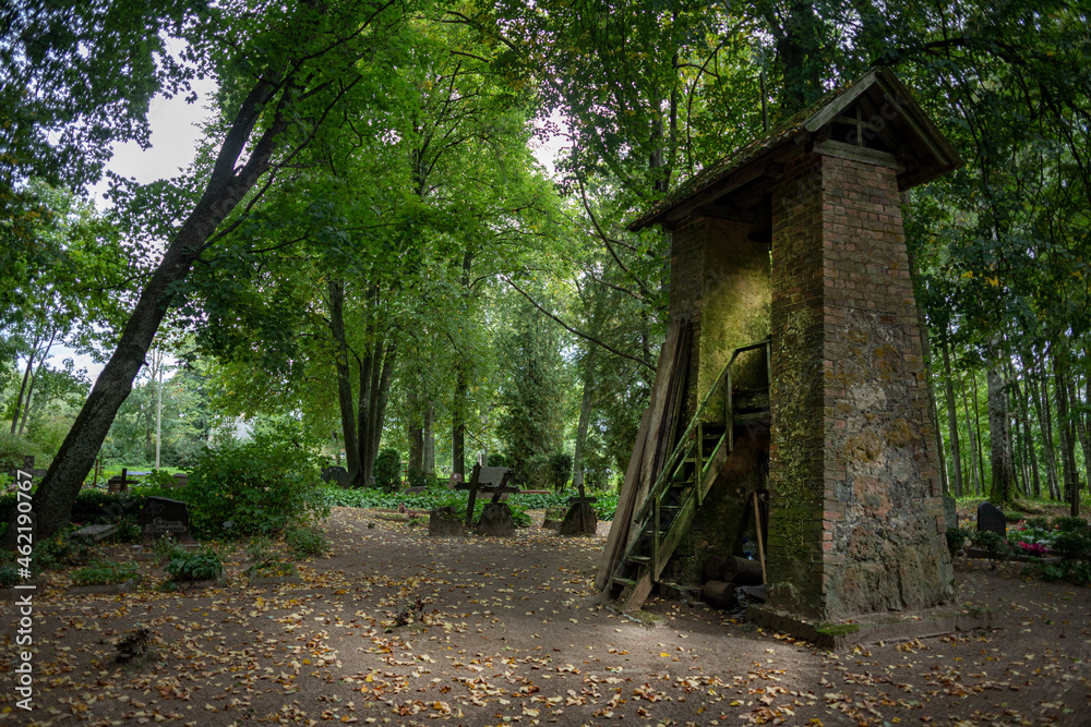 bell tover common in Latvia cemeteries. Landscape with old gravestones ...