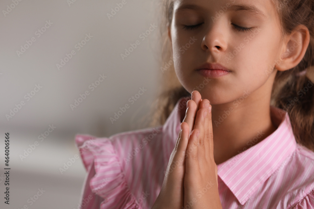 Cute little girl with hands clasped together praying on blurred ...