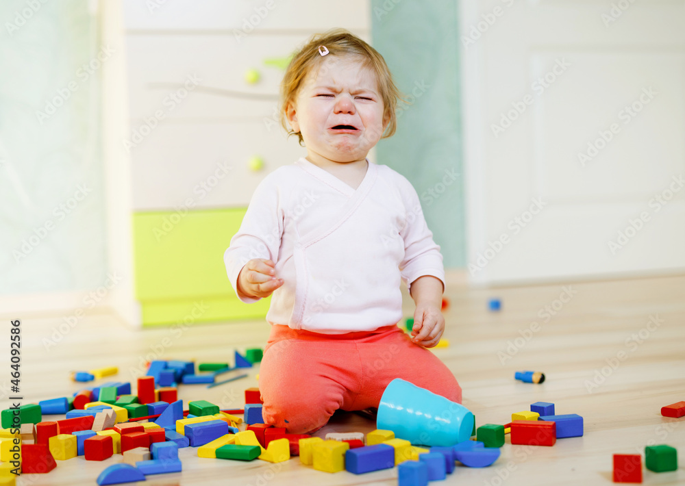 Upset crying baby girl with educational toys. Sad tired or hungry alone ...