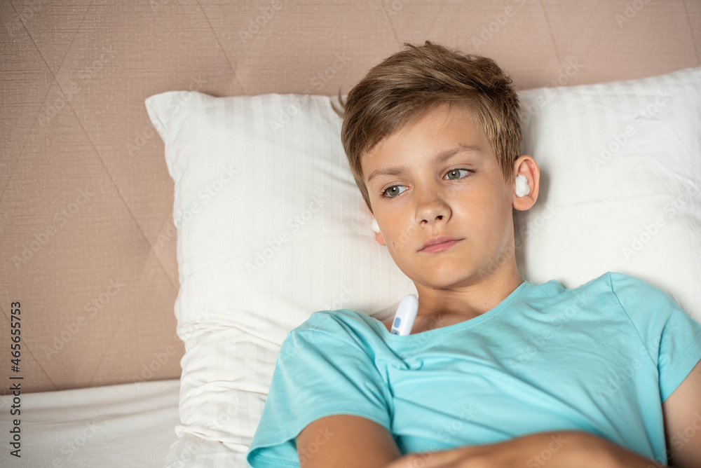 Teen boy suffering from otitis with sterile cotton wool in his ears ...
